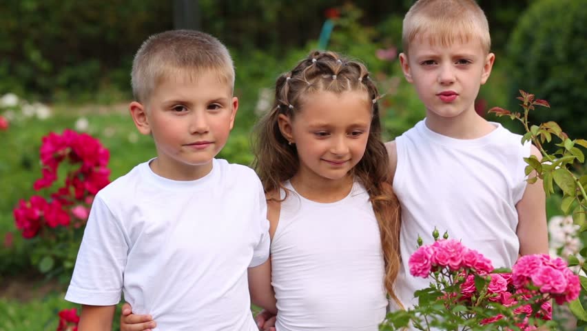 Two Boys And Girl In White Stand Among Flowers And Talk In Summer ...