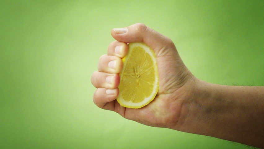 hand squeezing lemon on green background - 1080p - HD stock video clip