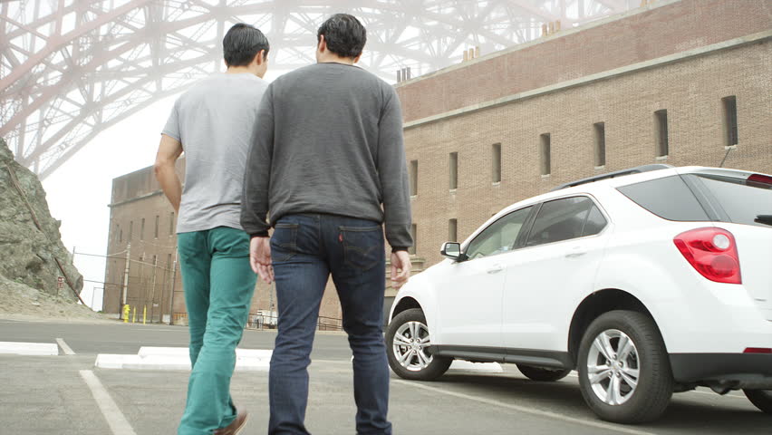 Two Men Walk To Their Car Sitting In The Parking Lot Under The Golden ...