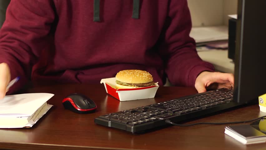 Man Eating Fast Food Hamburger And Working On Computer In Office Stock ...